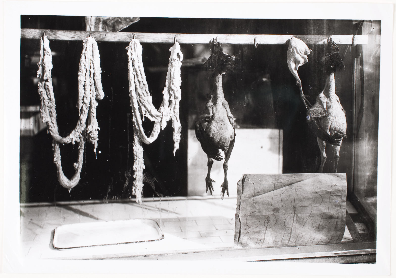 Entrails, two dead chickens on hoops, sign "Fresh/Cooked/Corned Beef ...